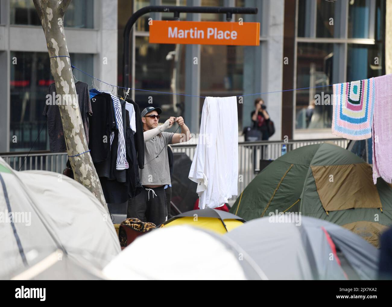 One of the residents of Tent City fixes a washing line amongst the ...