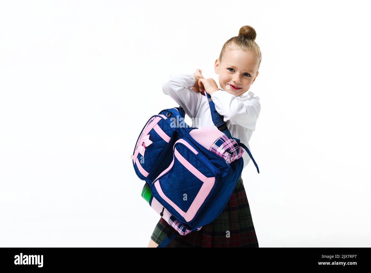 Cute girl in a school uniform with a big and heavy backpack on a white ...
