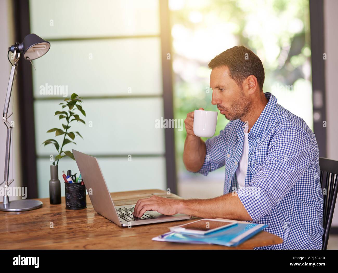 Getting the work day started with a cup of coffee. a young man working ...