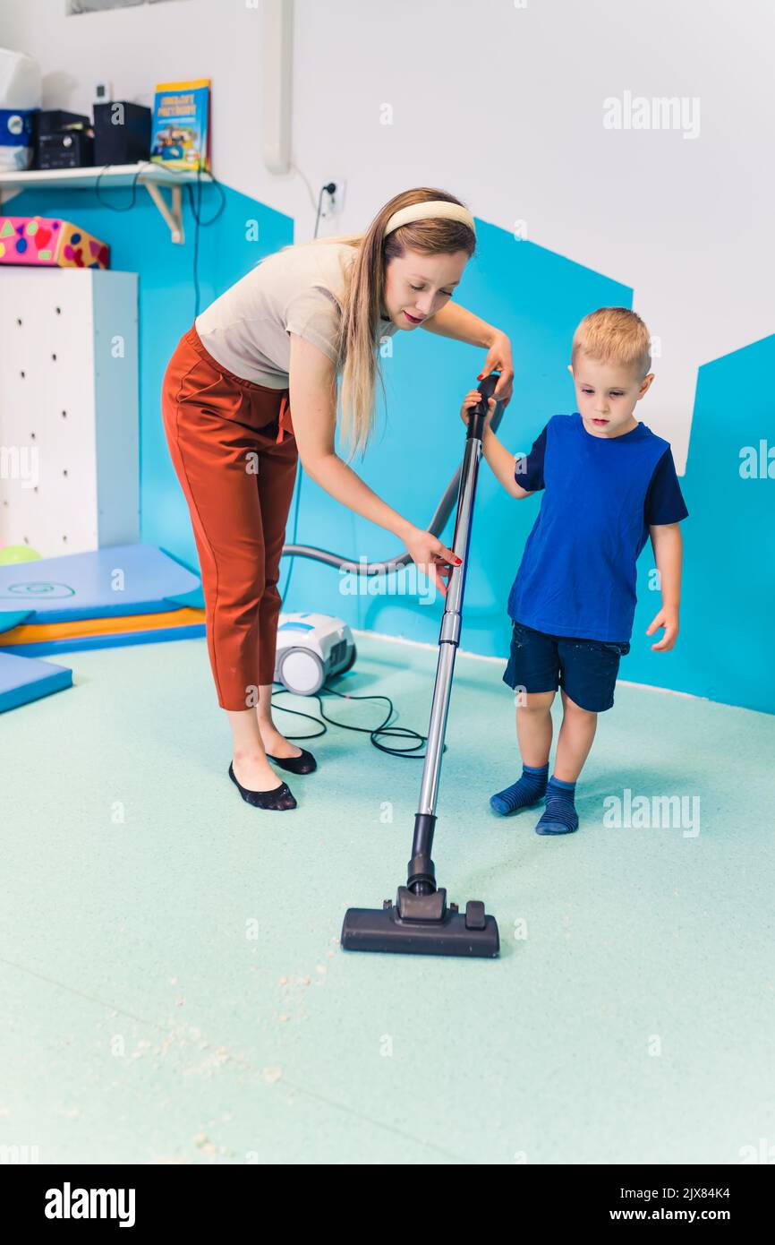 Little helper, toddler boy vacuuming, helping his teacher to clean the ...