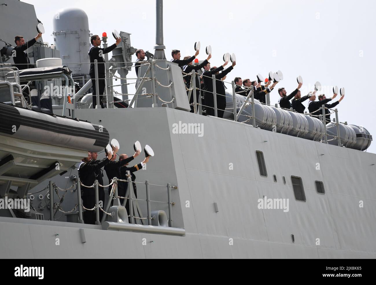The crew of HMAS Hobart raise their hats to cheer the ship after its ...