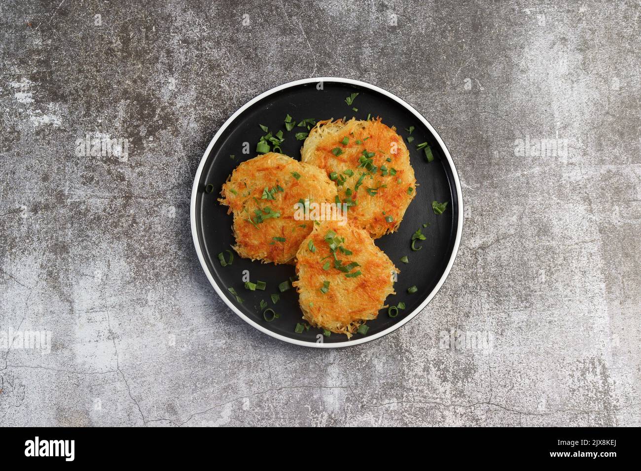 Rustic hash browns with chives on a round plate on a dark background ...