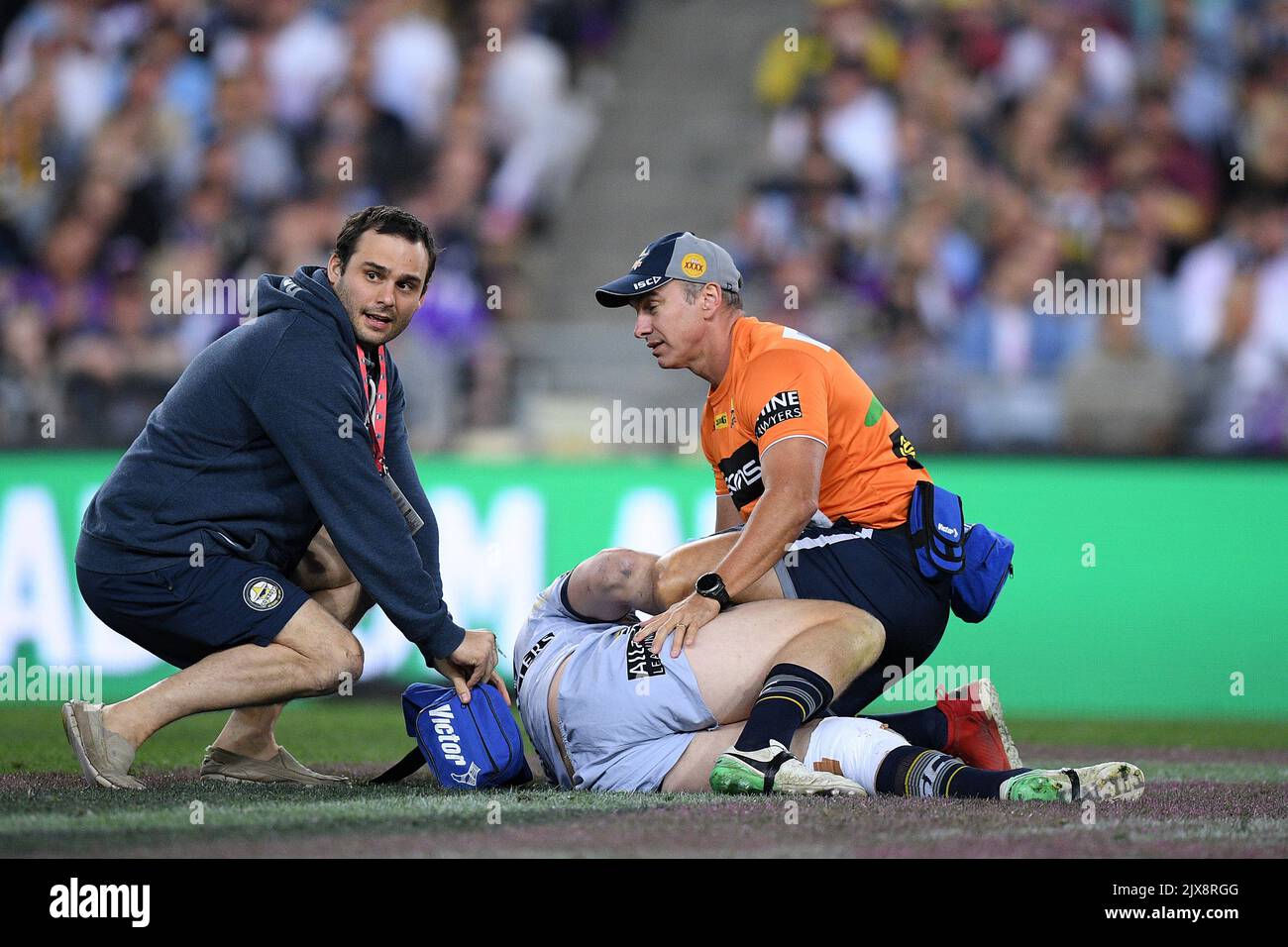 Shaun Fensom of the Cowboys is assisted by trainers during the NRL ...