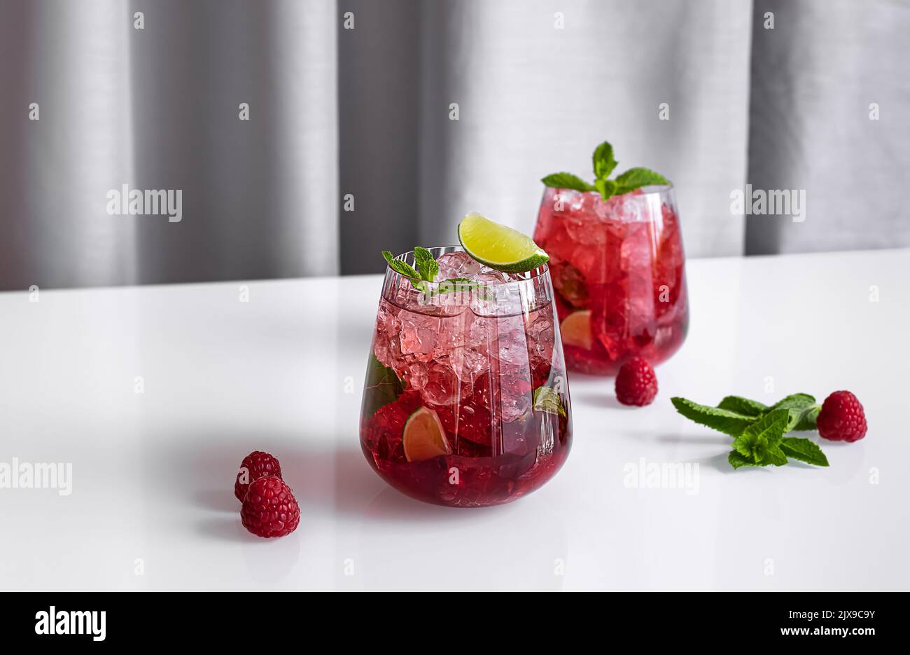 Fresh summer lemonade with raspberry, lime, soda water, and ice in ...