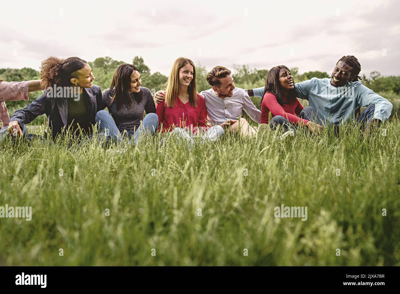 Multiracial International Community Of Happy Friends Sitting On Green