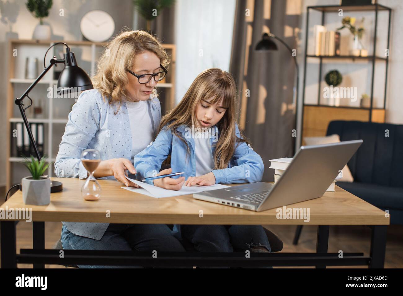 Young caucasian mother helping daughter remote studying at home ...