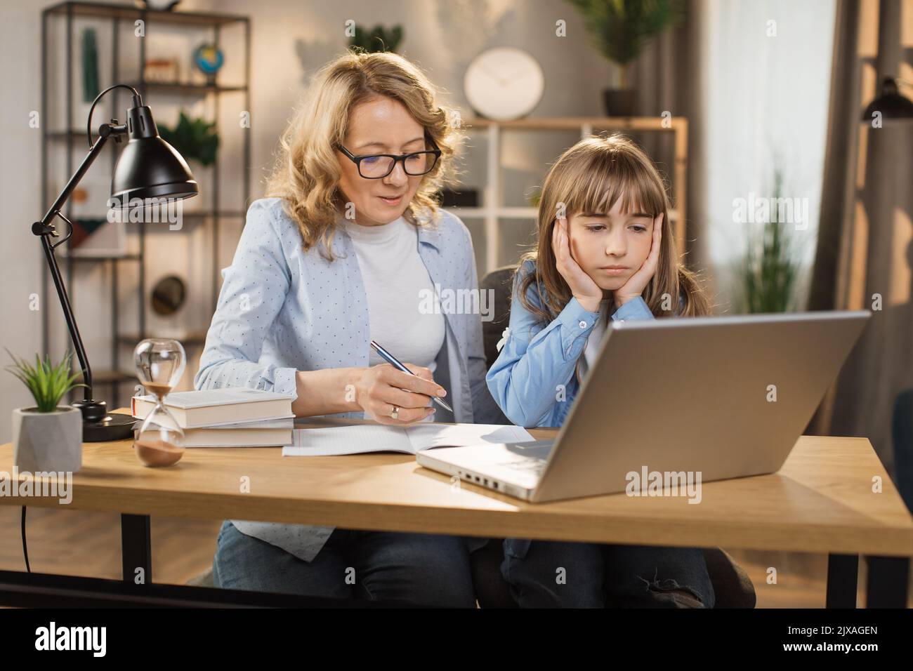 Caucasian tutor engaged with schoolgirl help complete tasks sitting at ...