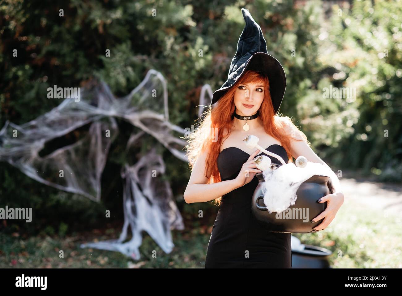 Halloween Beautiful young Witch girl in witches hat on spooky dark ...