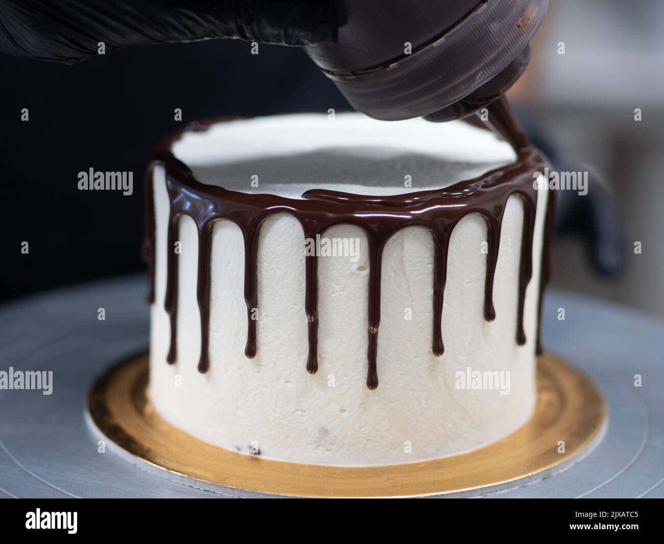 unrecognizable worker preparing a sweet dripping choco cake and berries ...