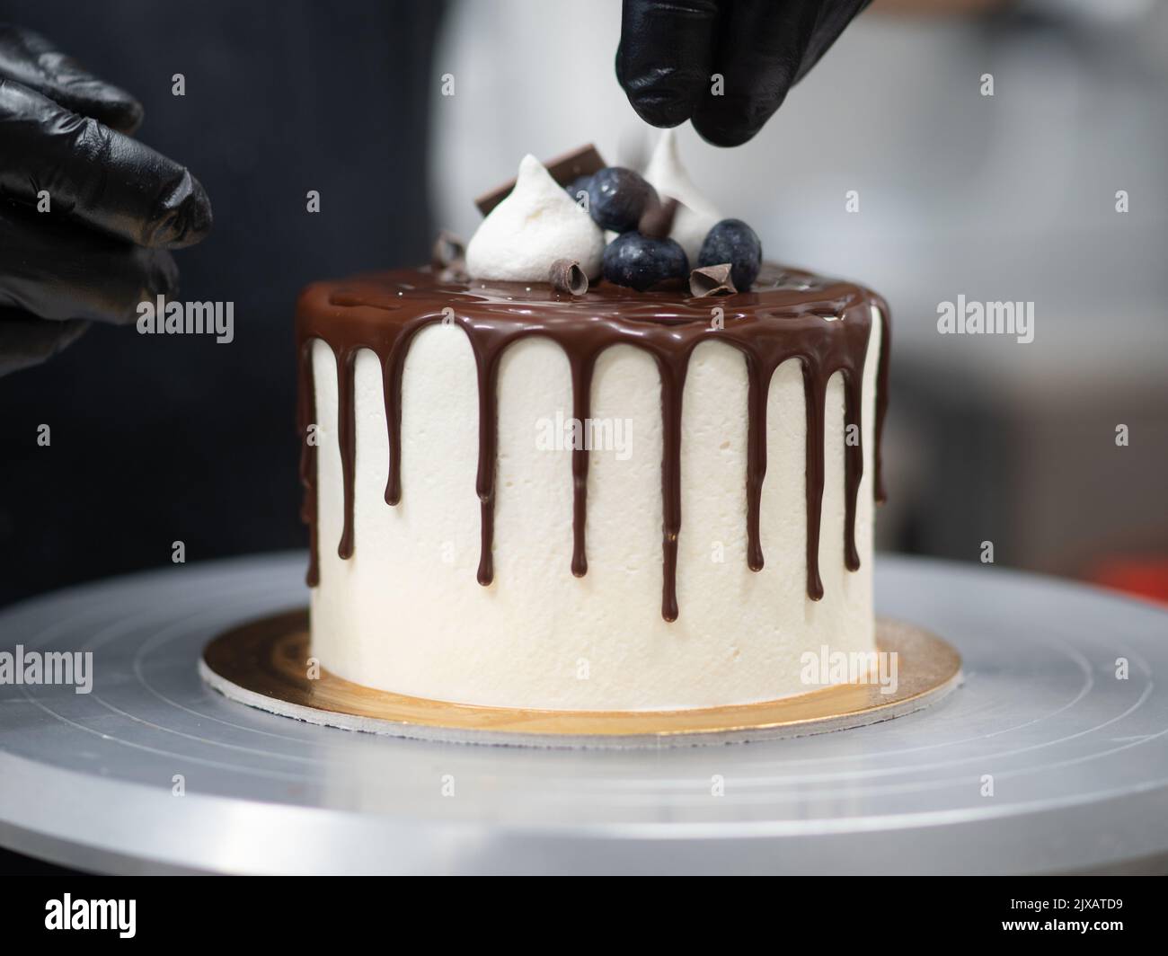 unrecognizable worker preparing a sweet dripping choco cake and berries ...