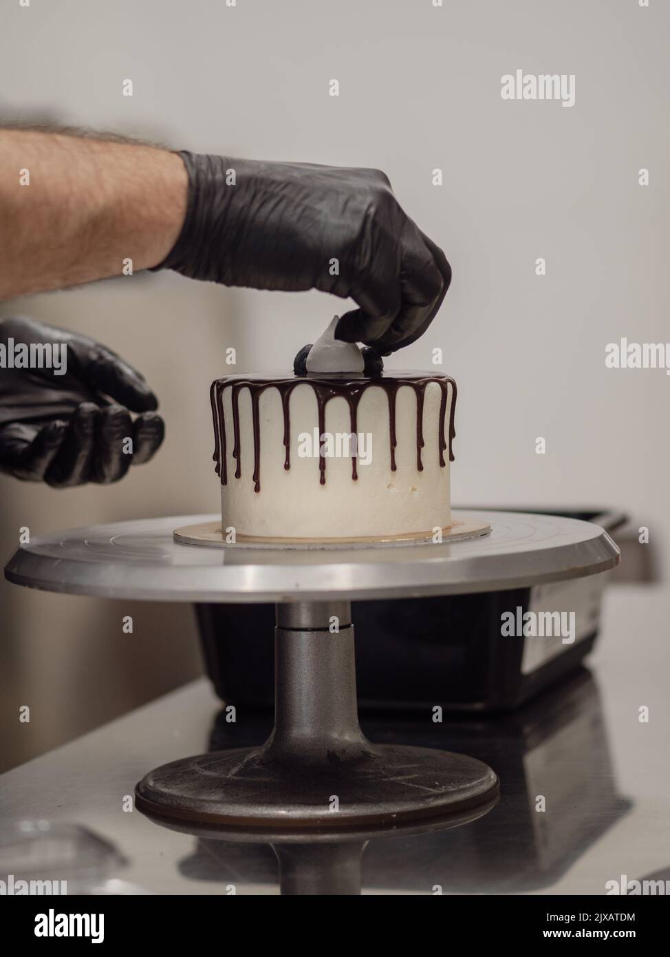 unrecognizable worker preparing a sweet dripping choco cake and berries ...