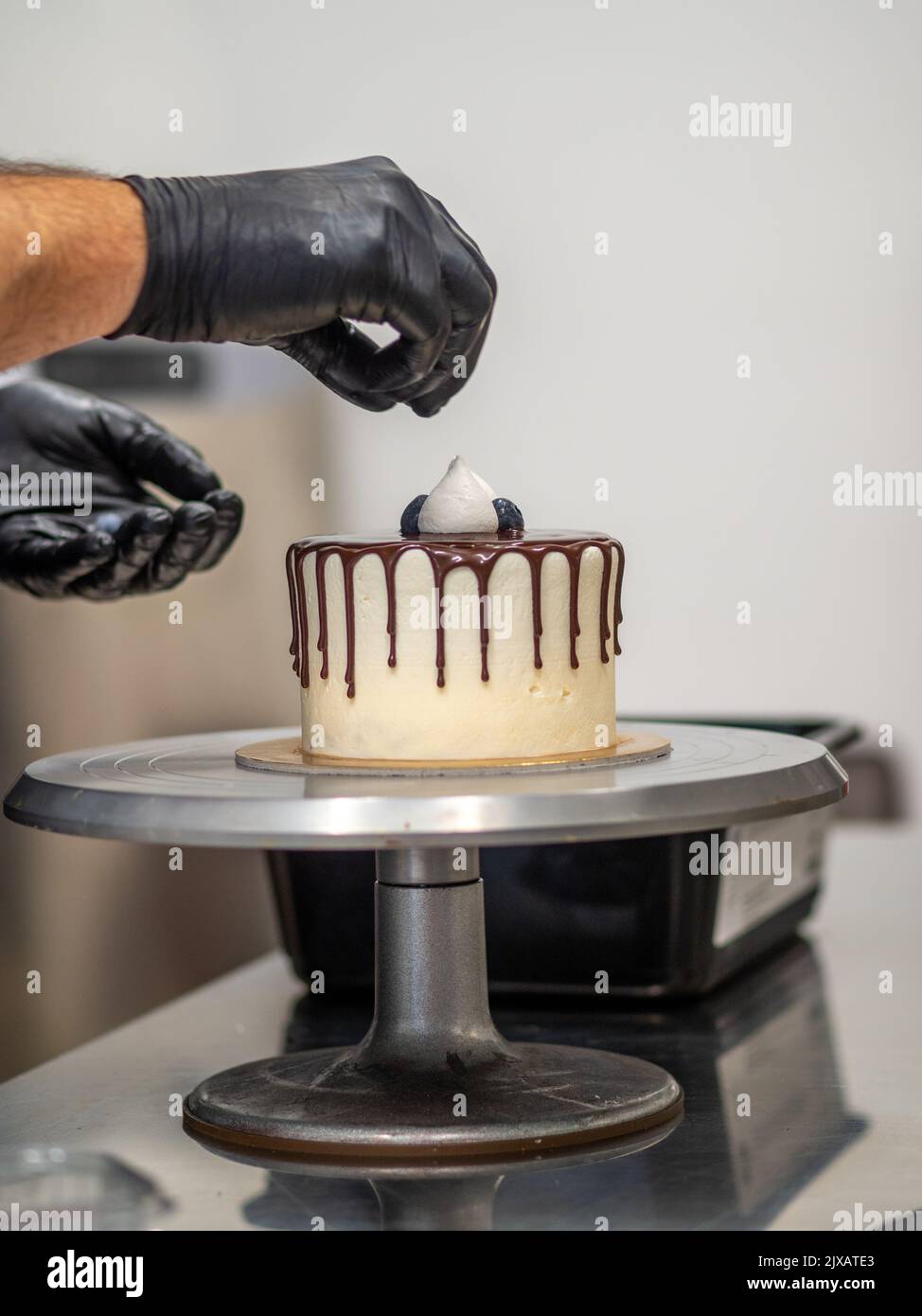 unrecognizable worker preparing a sweet dripping choco cake and berries ...