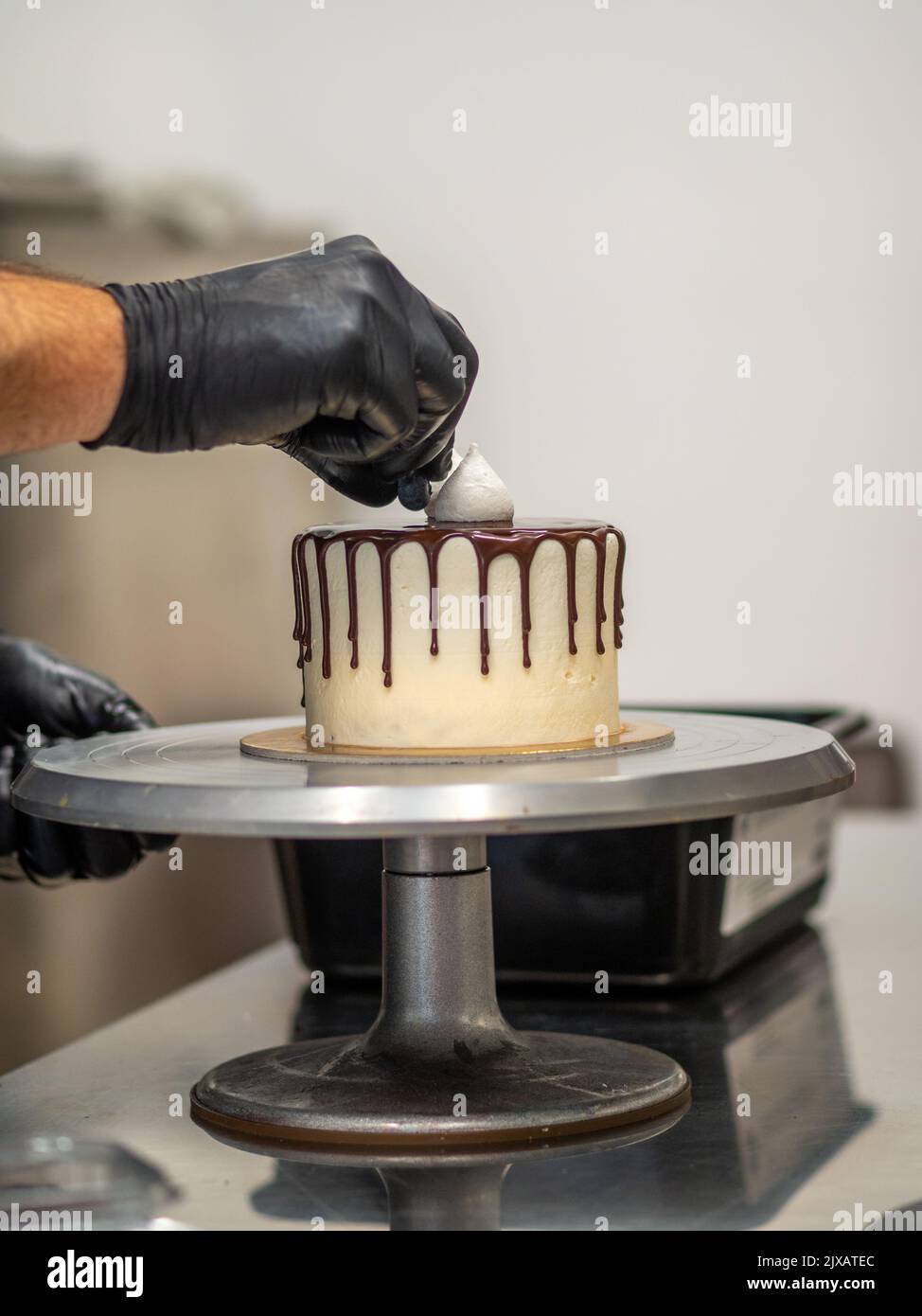 unrecognizable worker preparing a sweet dripping choco cake and berries ...