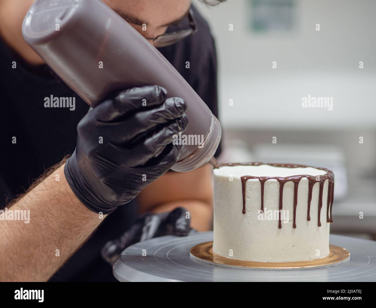 unrecognizable worker preparing a sweet dripping choco cake and berries ...