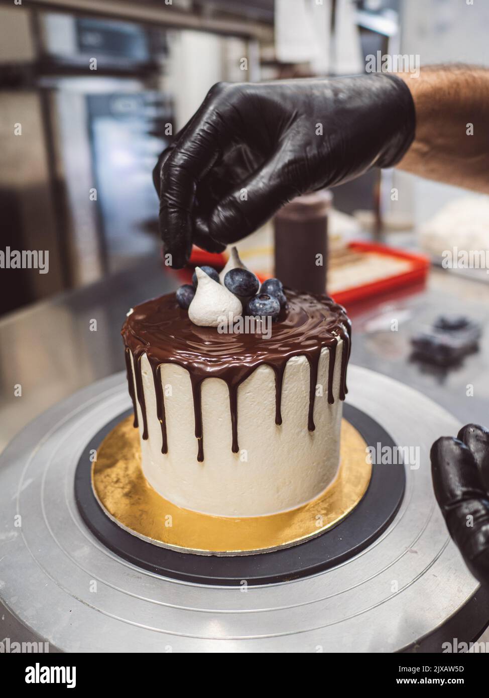 unrecognizable worker preparing a sweet dripping choco cake and berries ...