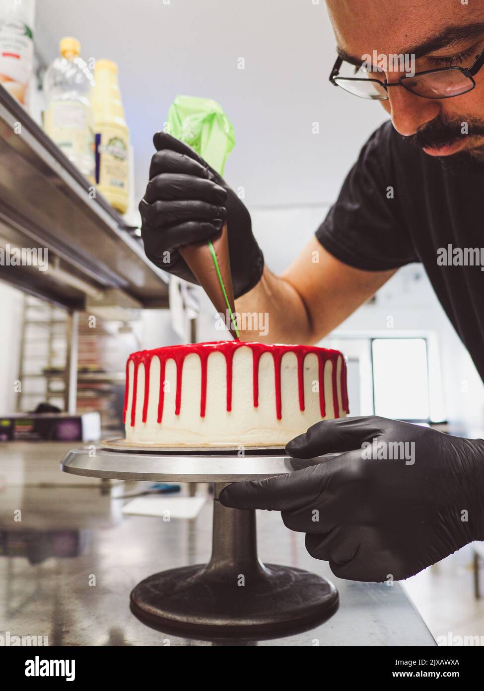 chef making for icing a red drip cake in the professional kitchen lab ...