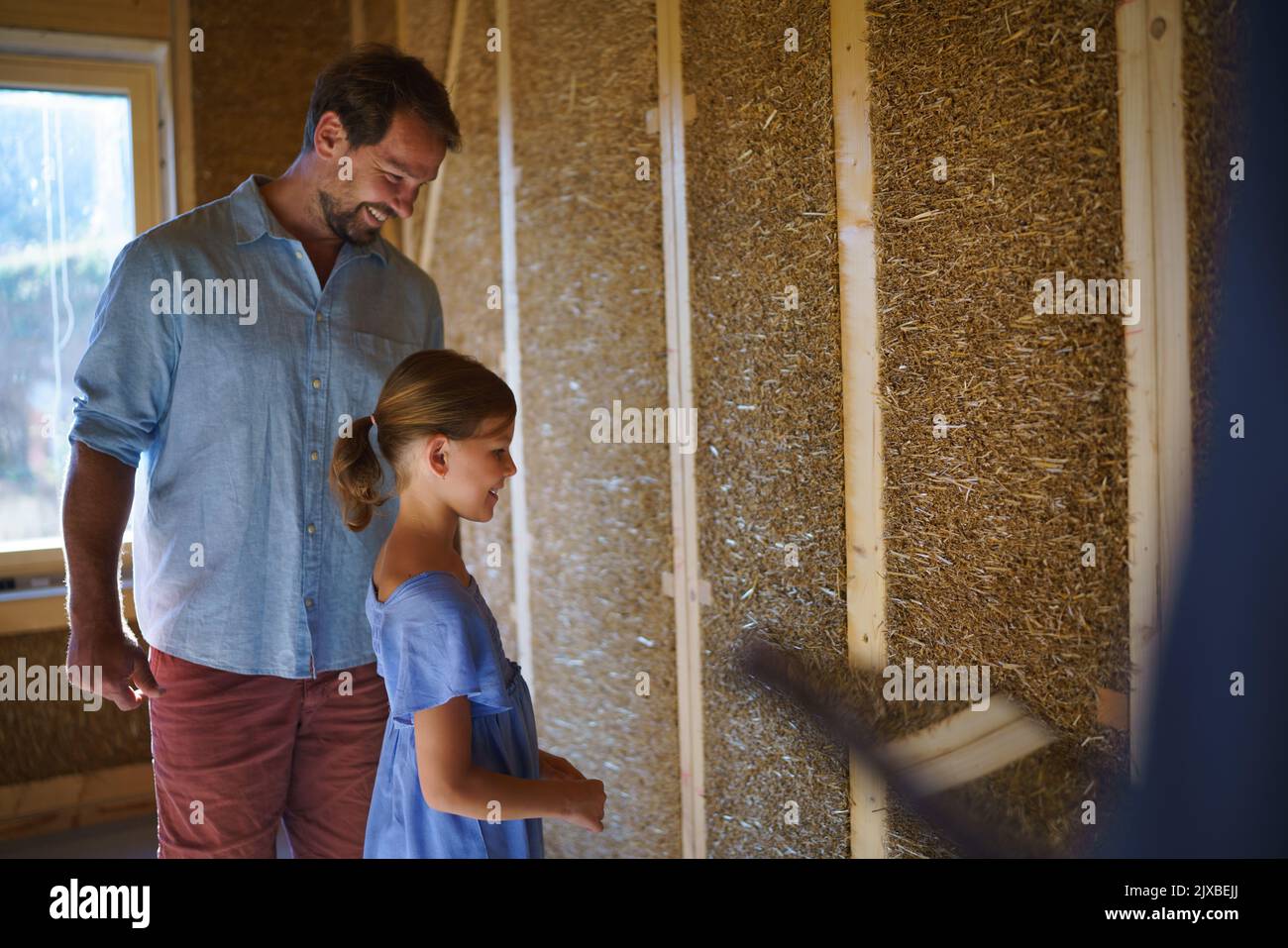 Father with his little daughter checking their unfinished wooden house ...
