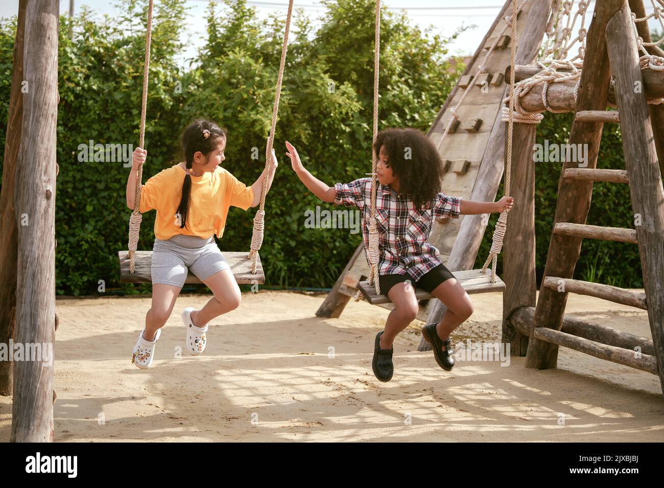Two kids girl are playing on the swing in the outdoor playground Stock ...