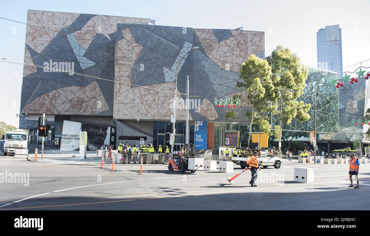 Workers place security bollards at the corner of Russell and Flinders ...