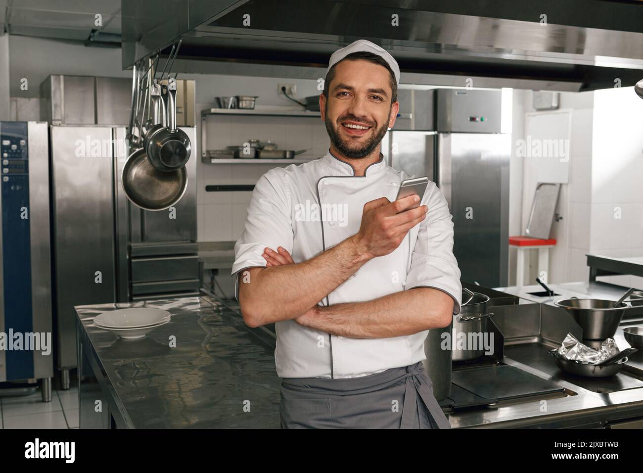 Chef cook using smart phone at the restaurant kitchen and looking ...