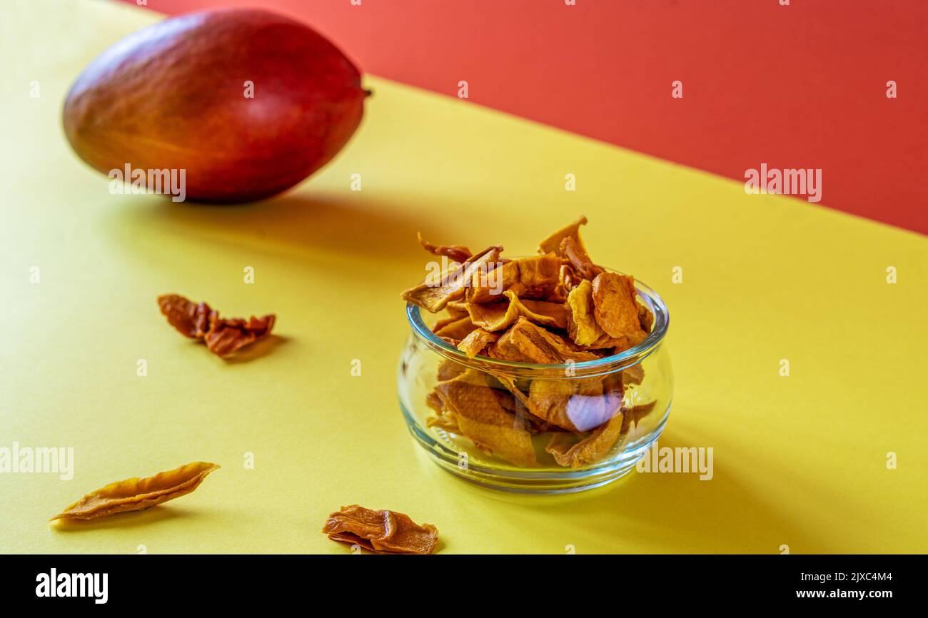Mango chips in a glass jar over yellow and orange background Stock ...