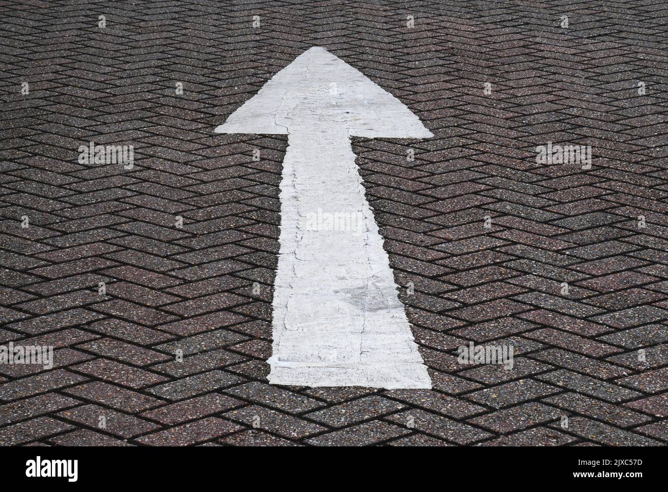 White arrow sign in car park on block paving Stock Photo - Alamy