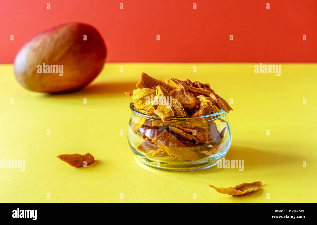 Mango chips in a glass jar over yellow and orange background Stock ...