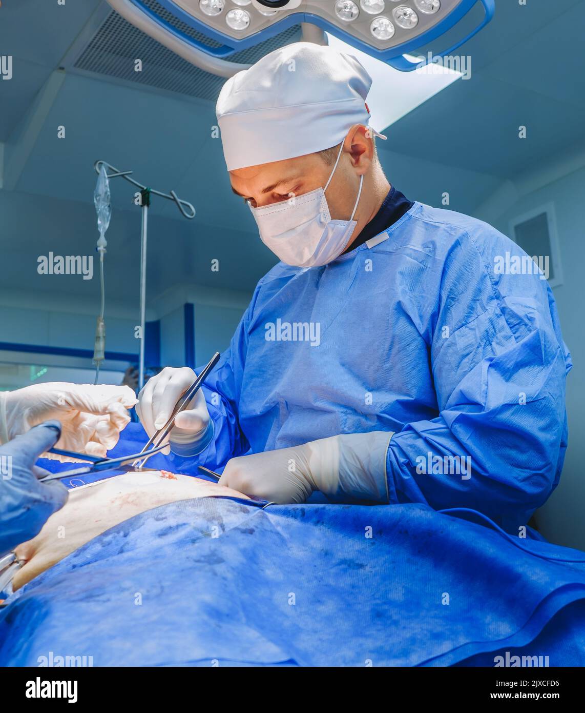 Male surgeon operating on patient's body with surgical instruments ...