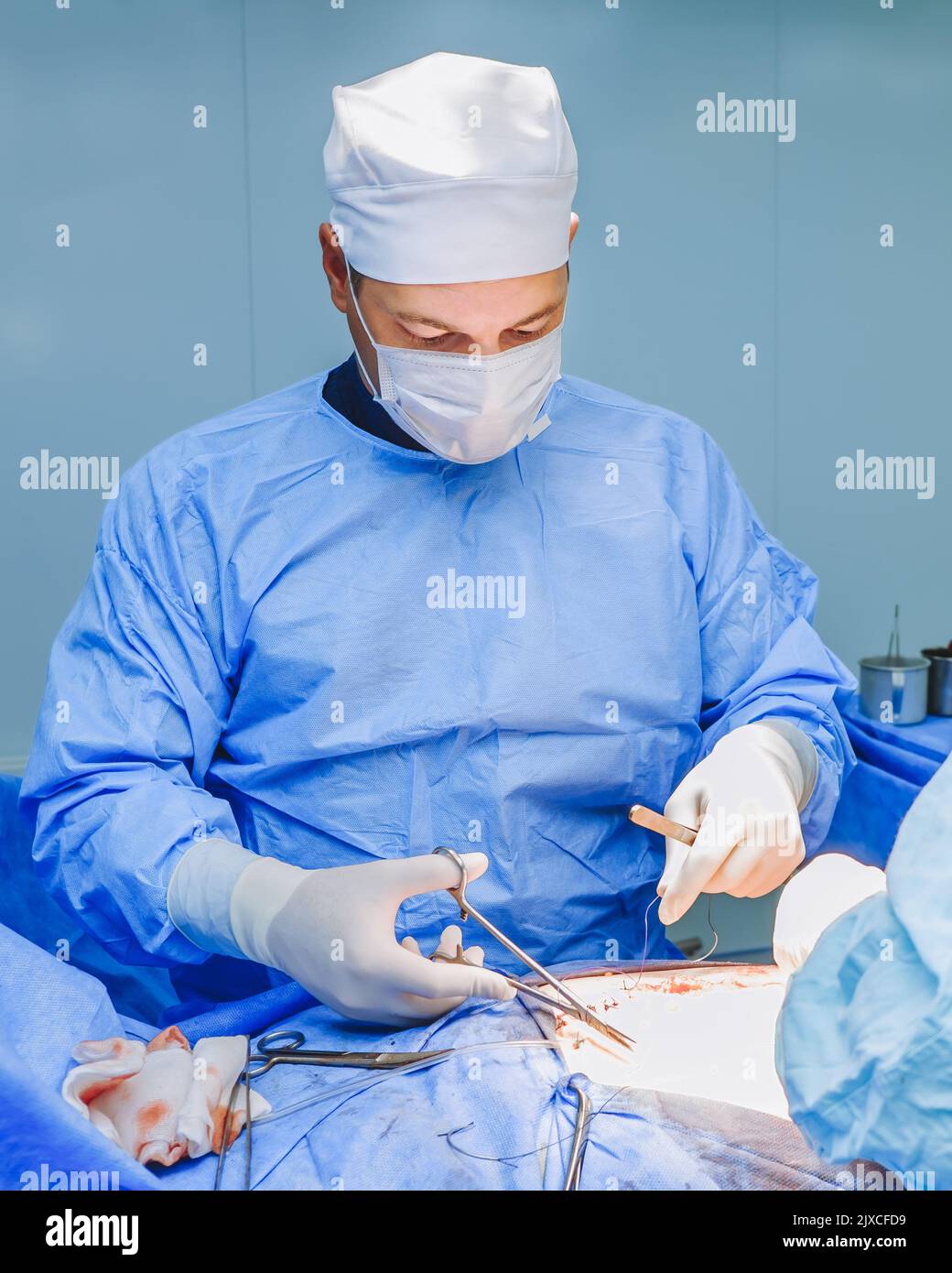 The surgeon sews up the skin of the patient at the end of surgery. A ...