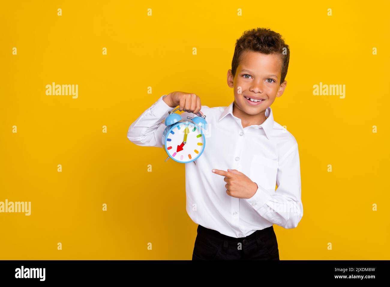 Portrait of positive cute boy indicate finger hand hold classic clock ...