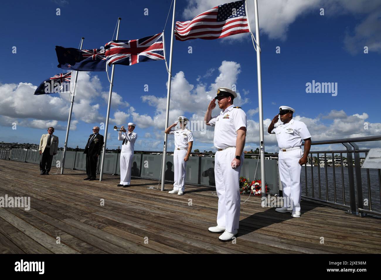 United States and Australian Navy officers salute while flags are ...