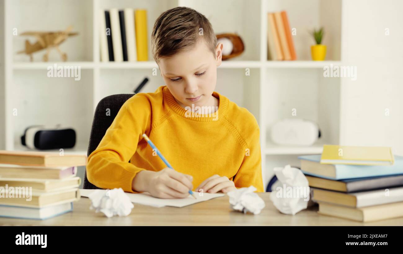 preteen schoolboy drawing near crumpled papers and books on desk,stock ...