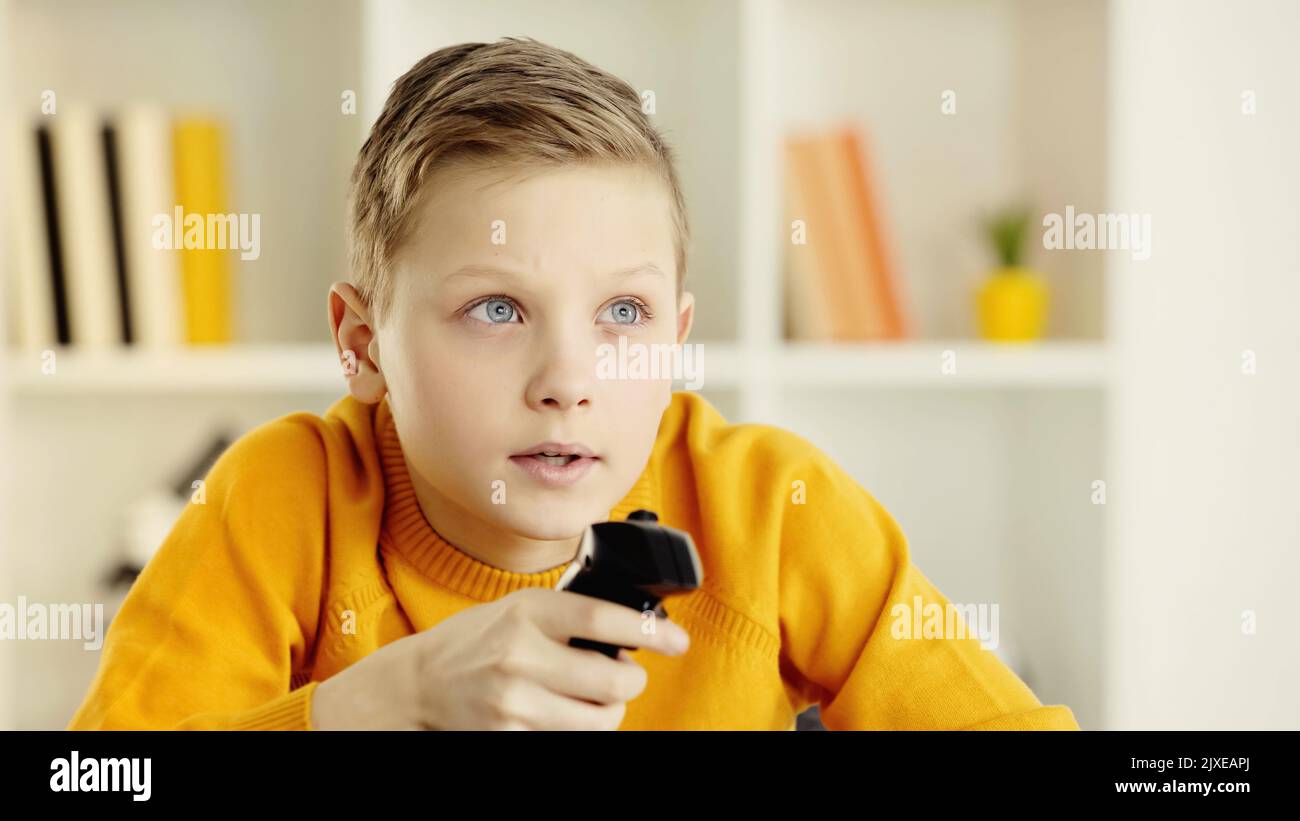 boy with blue eyes looking away while playing video game at home,stock ...