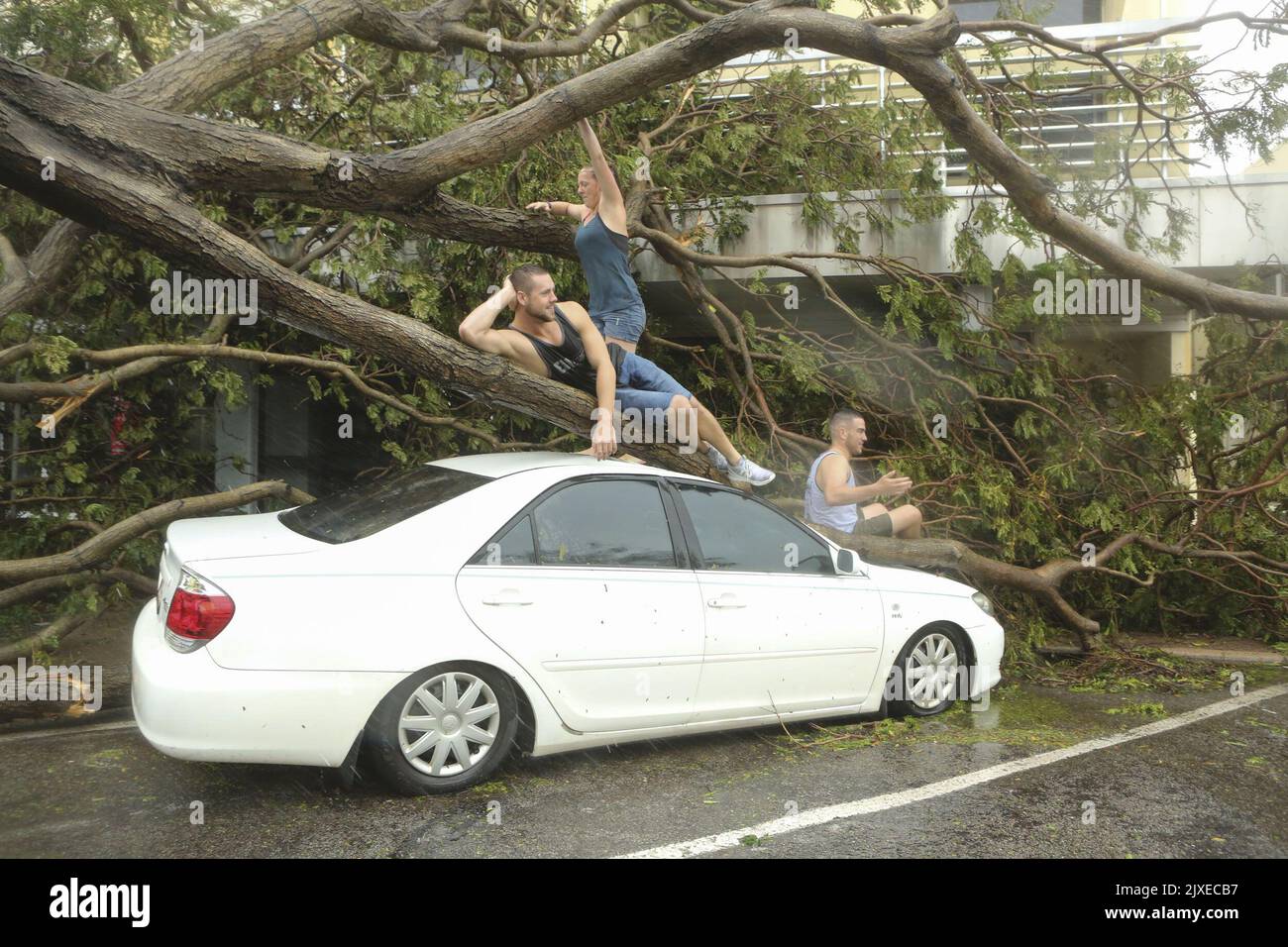 Tourists pose for selfies on top of a damaged car after Tropical ...