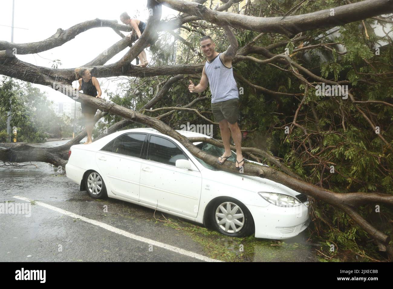 Tourists pose for selfies on top of a damaged car after Tropical ...