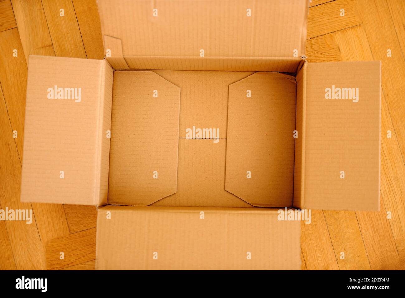 Open empty cardboard parcel on the wooden parquet floor - delivery ...