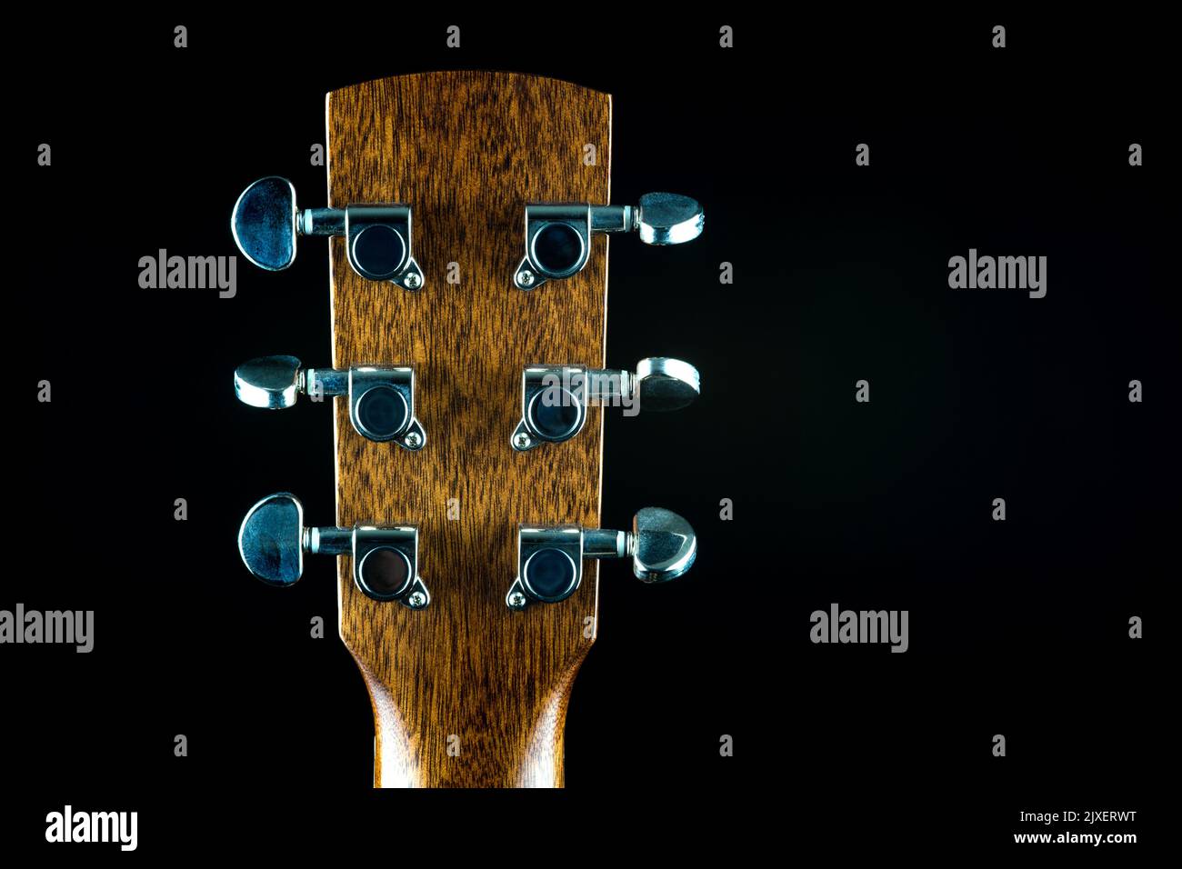 Rear view of acoustic guitar peg head isolated against a black ...