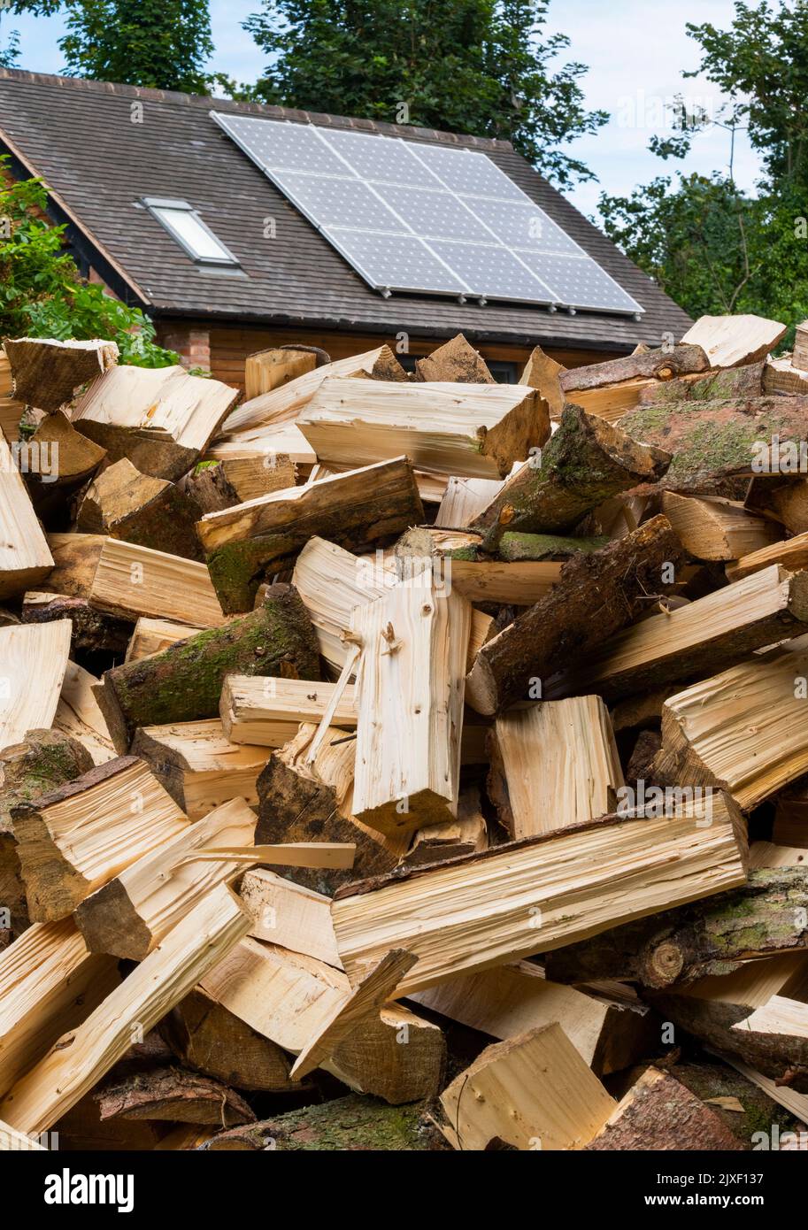 A pile of split logs and solar panels on a roof Stock Photo - Alamy