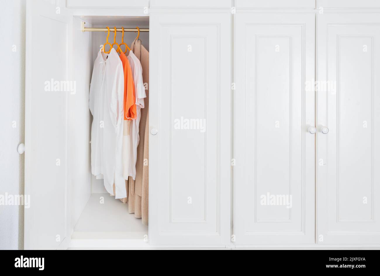 White wardrobe with collection of clothes hanging on in dressing room ...