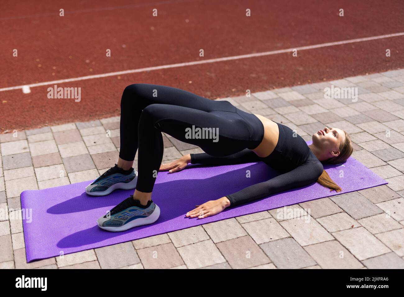 Fit young woman training on mat outdoor summer day, performing reverse ...