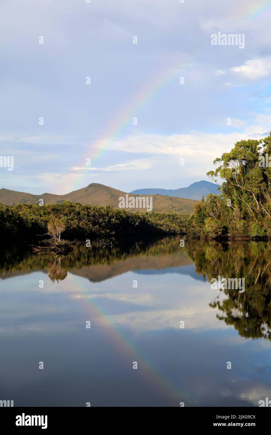 A rainbow is reflected in the water of Port Davey River in Tasmania's Wilderness World Heritage ...