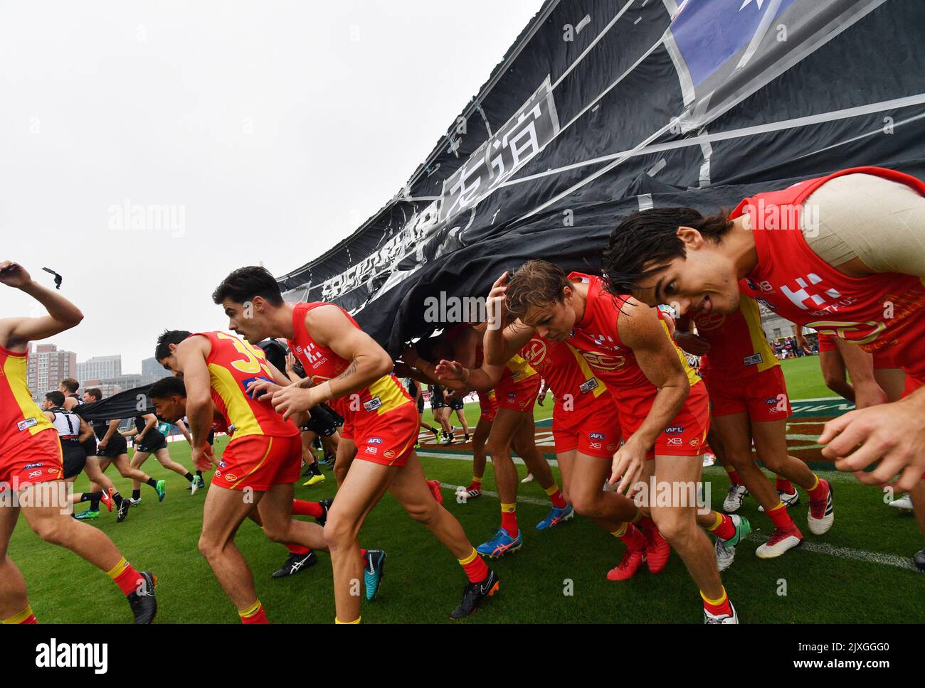 Gold Coast players run through the banner during the Round 9 AFL match ...