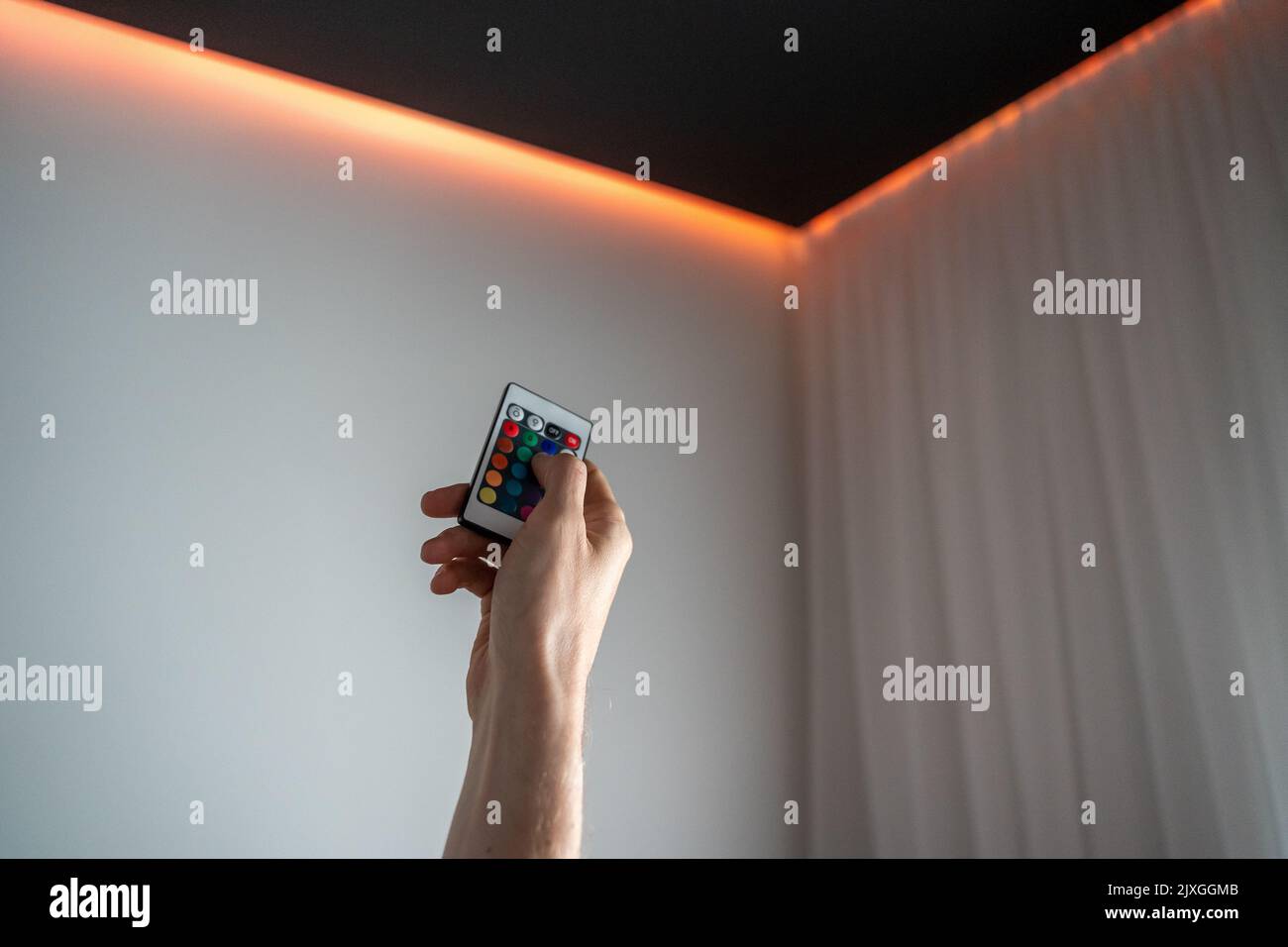 Hand holding led lighting remote control with light turned on ceiling ...