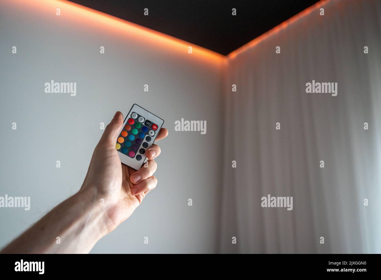 Hand holding led lighting remote control with light turned on ceiling ...