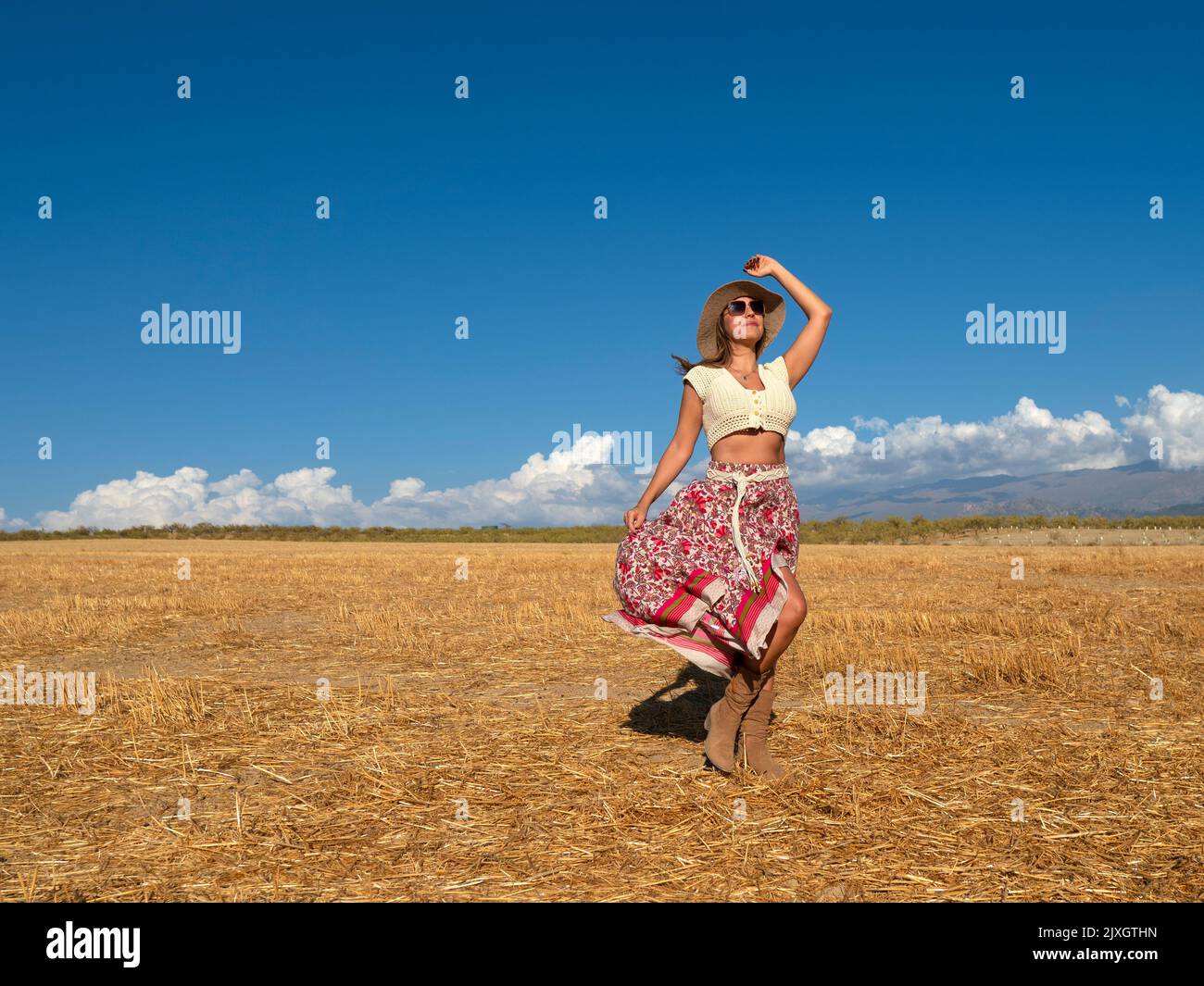 Full body female in boho outfit raising hand and touching skirt while ...