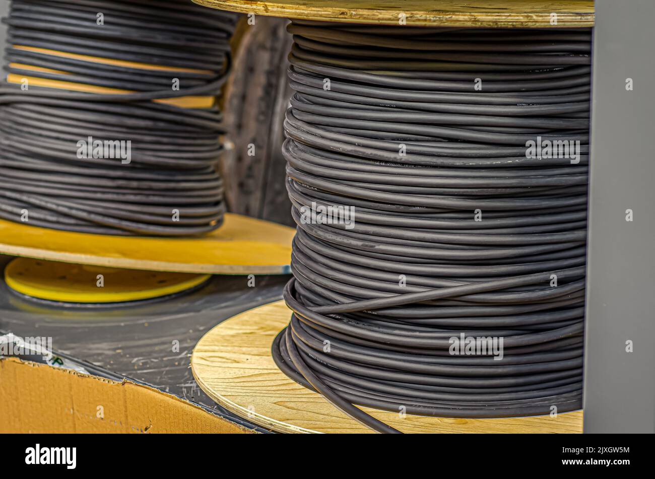 Big wooden spool with black cable in the plant close-up Stock Photo - Alamy
