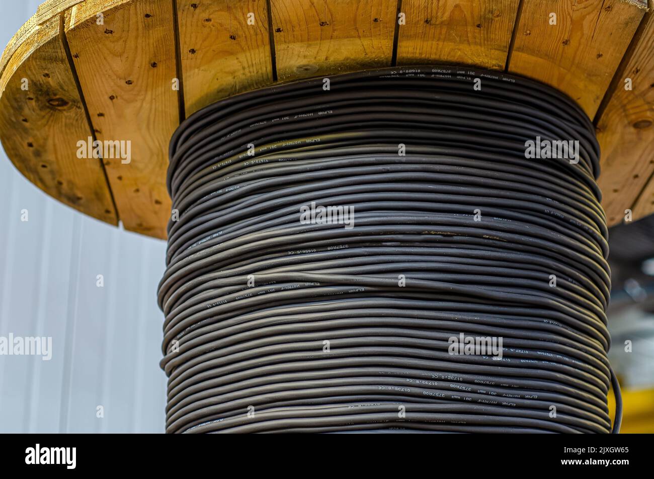 Big wooden spool with black cable in the plant close-up Stock Photo - Alamy