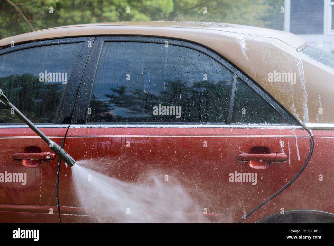 A worker washes his car under high pressure jet sprays of water along ...