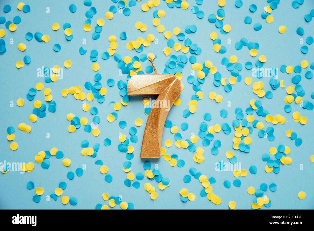 Number 7 seven golden celebration birthday candle on yellow and blue ...