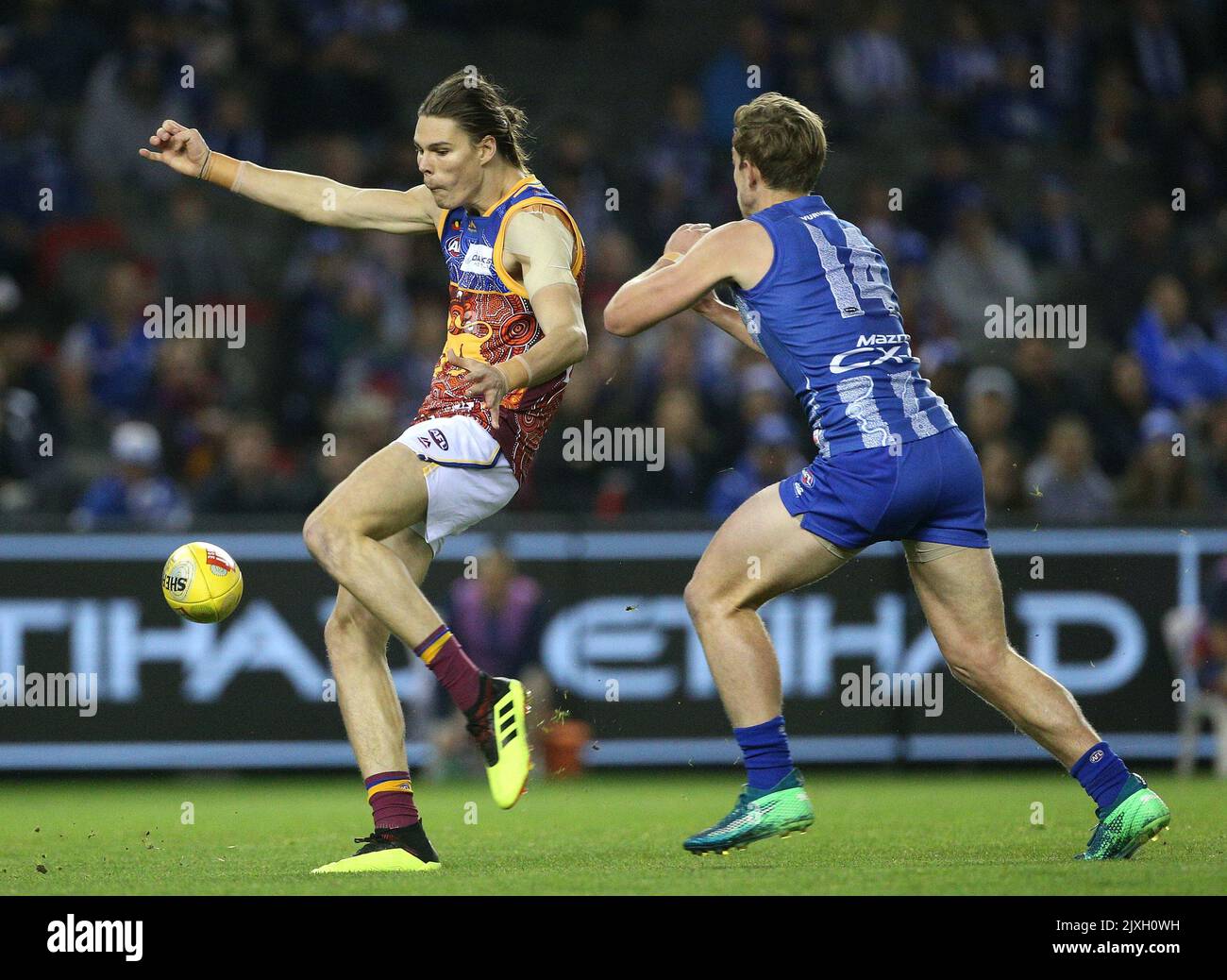 Eric Hipwood of the Lions kicks under pressure from Trent Dumont of the ...